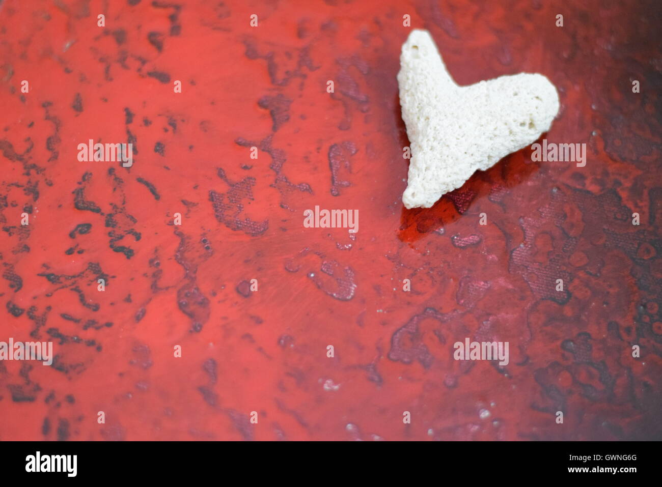 A white heart stone with red and black background Stock Photo - Alamy