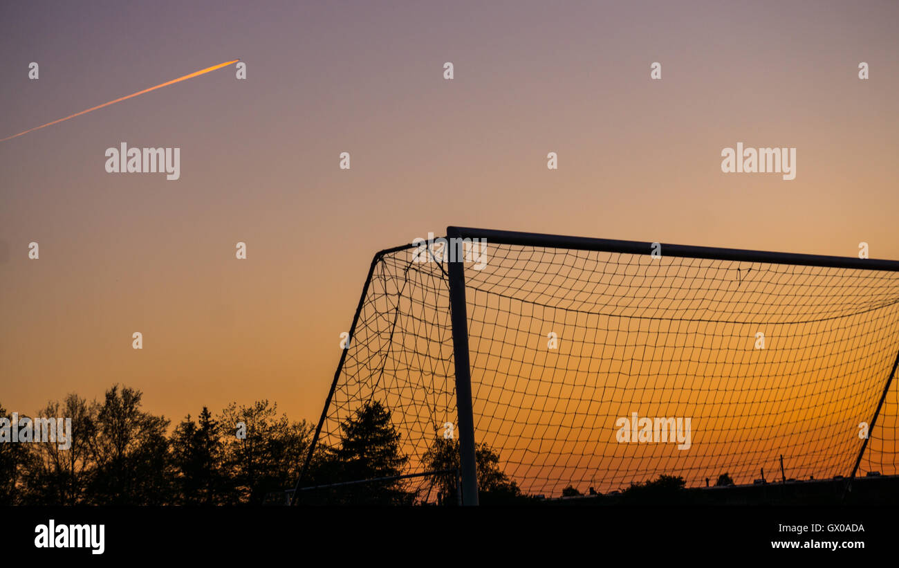 Sun setting over football goal while plane is flying far away Stock ...