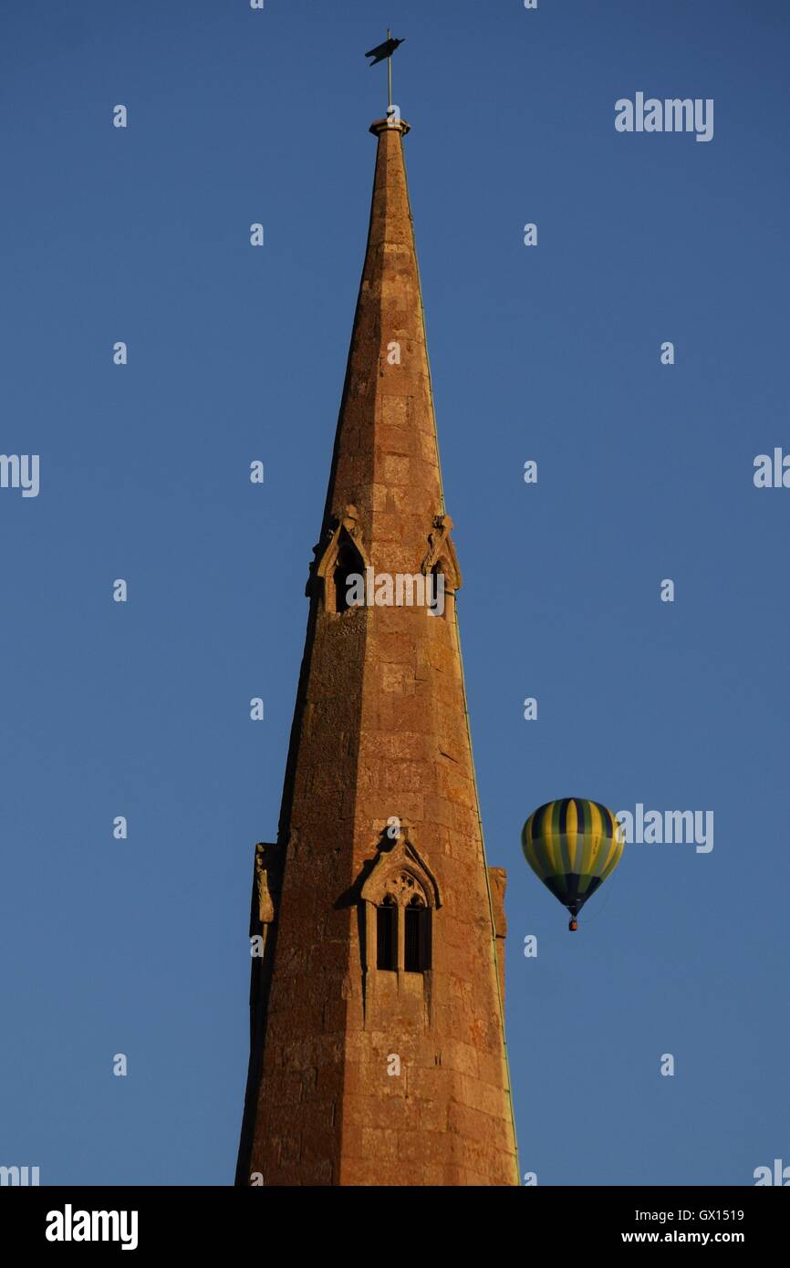 A hot air balloon flying behind a church spire Stock Photo - Alamy