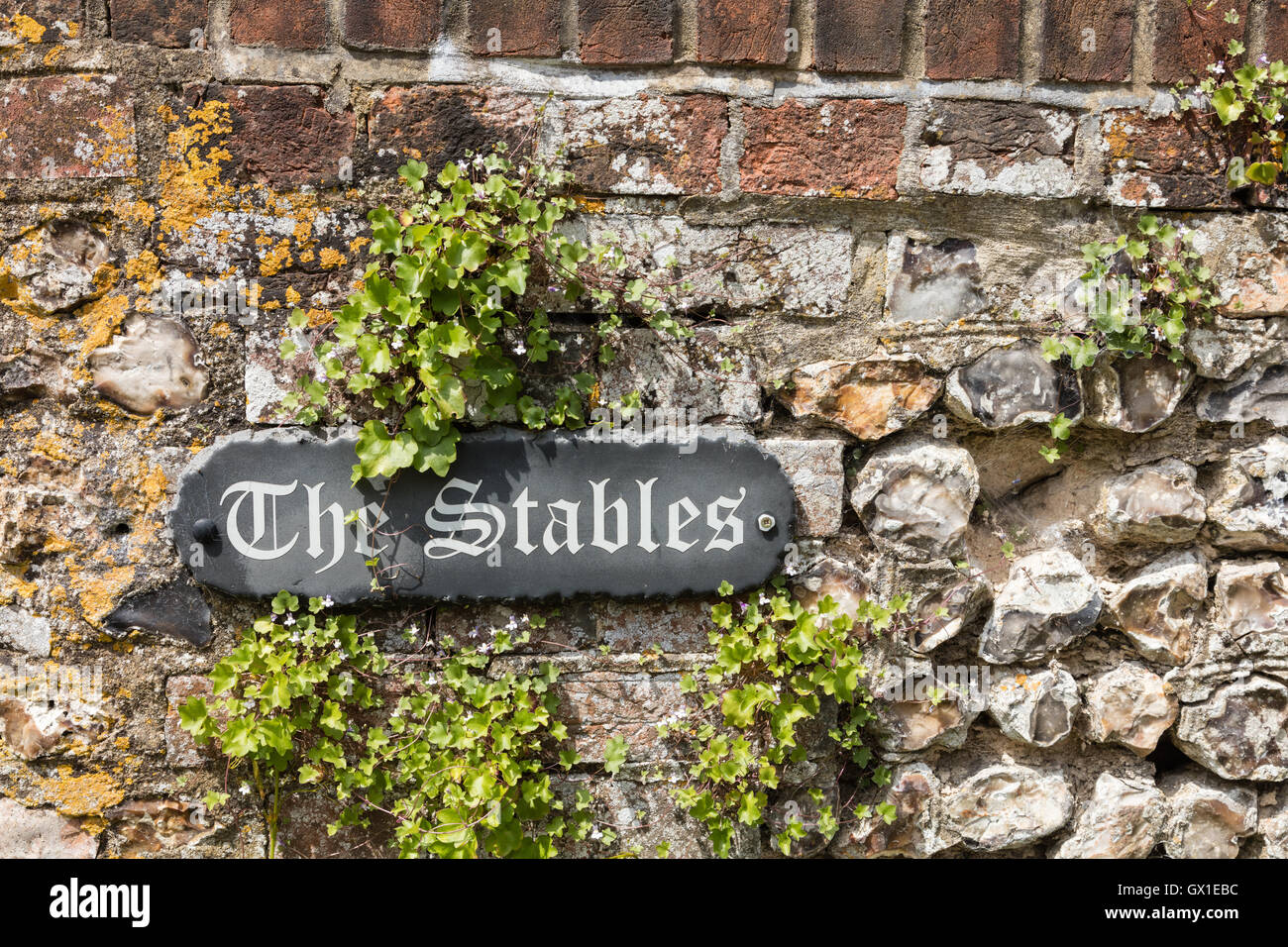 Slate house name "The Stables" on a flint and brick wall in Chawton ...