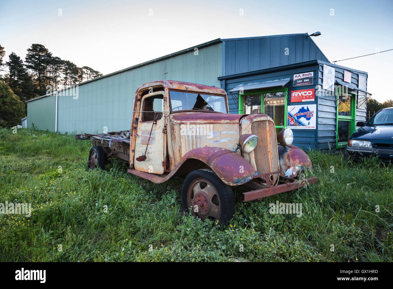 A rusty old truck, in tall grass, beside a second hand car yard Stock ...