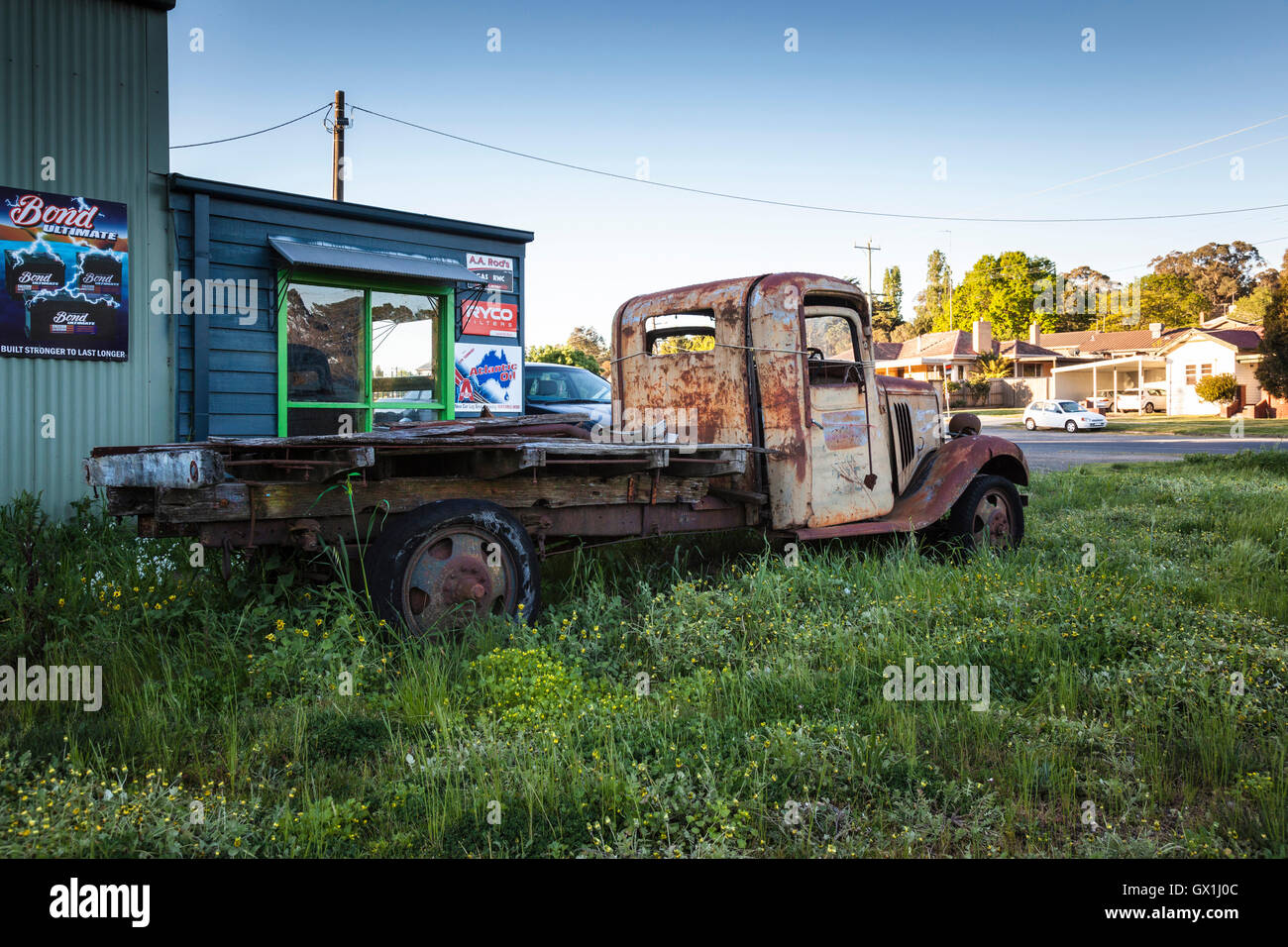 A rusty old truck, in tall grass, beside a second hand car yard Stock ...