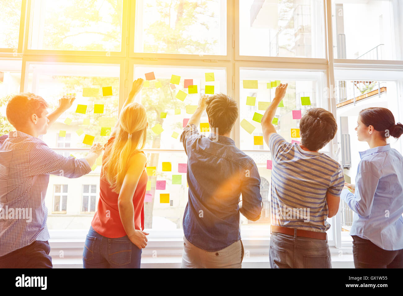 Students putting sticky notes on window for planning analysis Stock ...