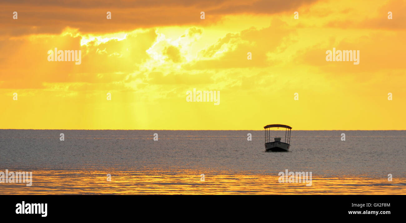 Golden ocean sunset with a boat silhouette Stock Photo - Alamy