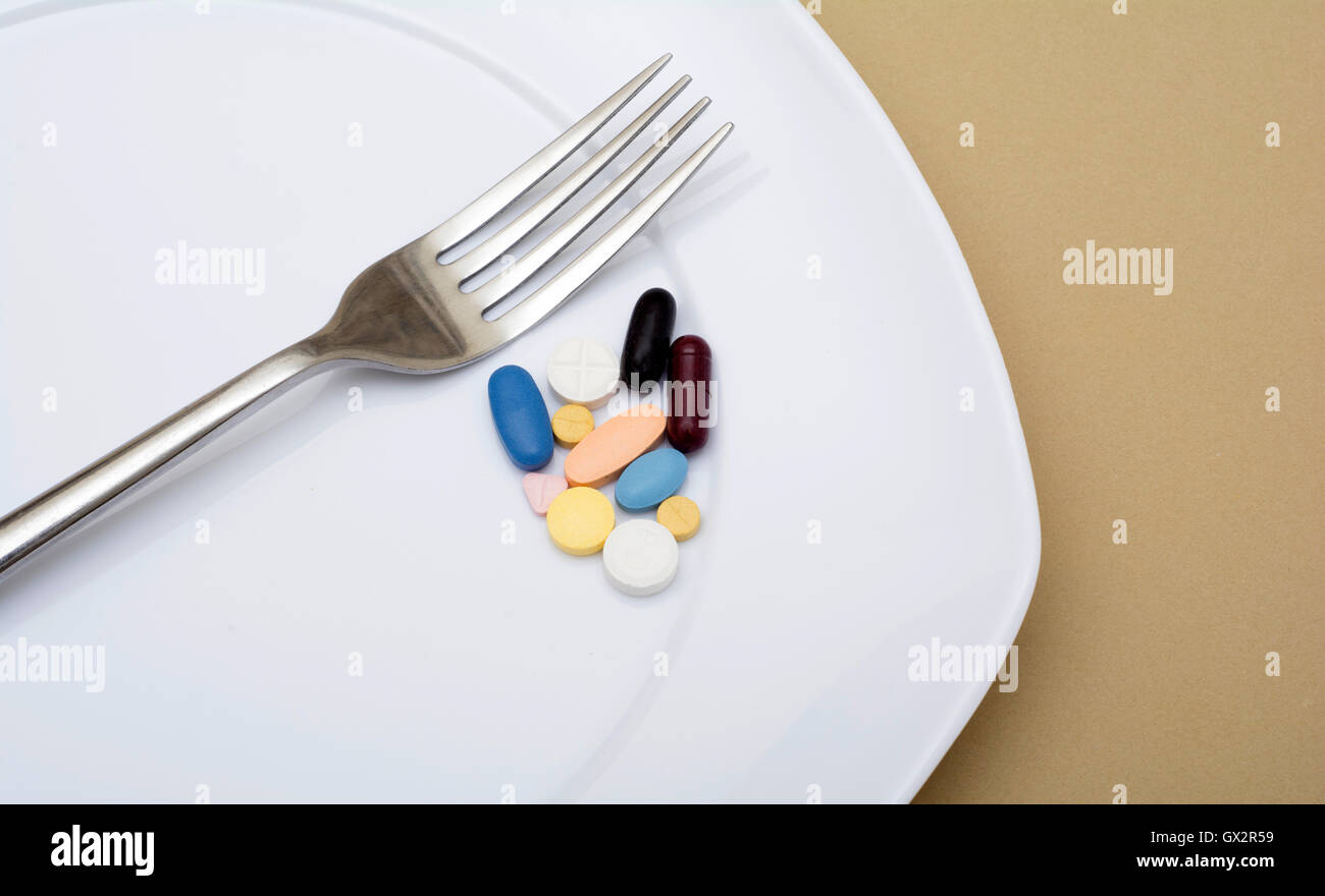 Colorful capsules and pills on plate with fork, knife - healthy diet ...
