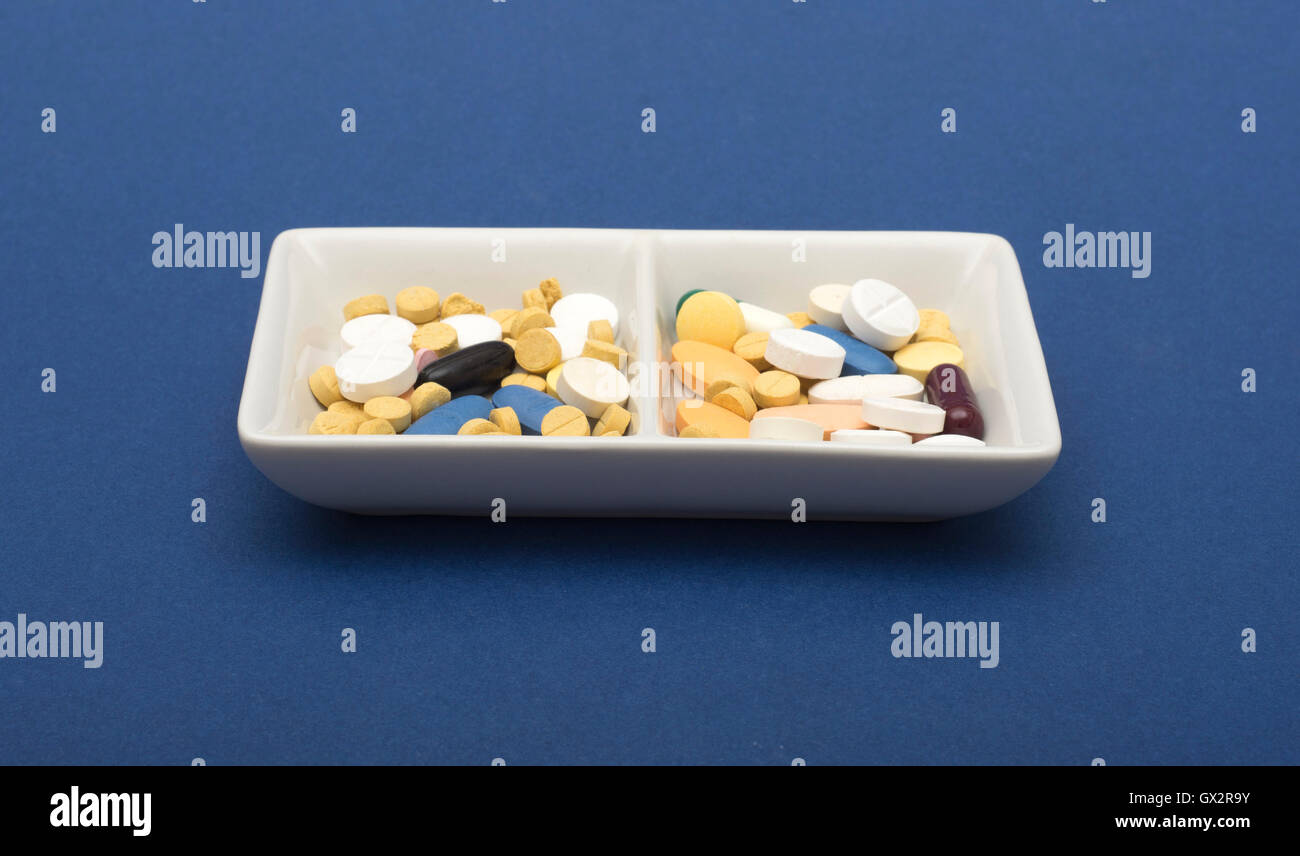 Different Capsule and tablets in plate on blue background Stock Photo ...