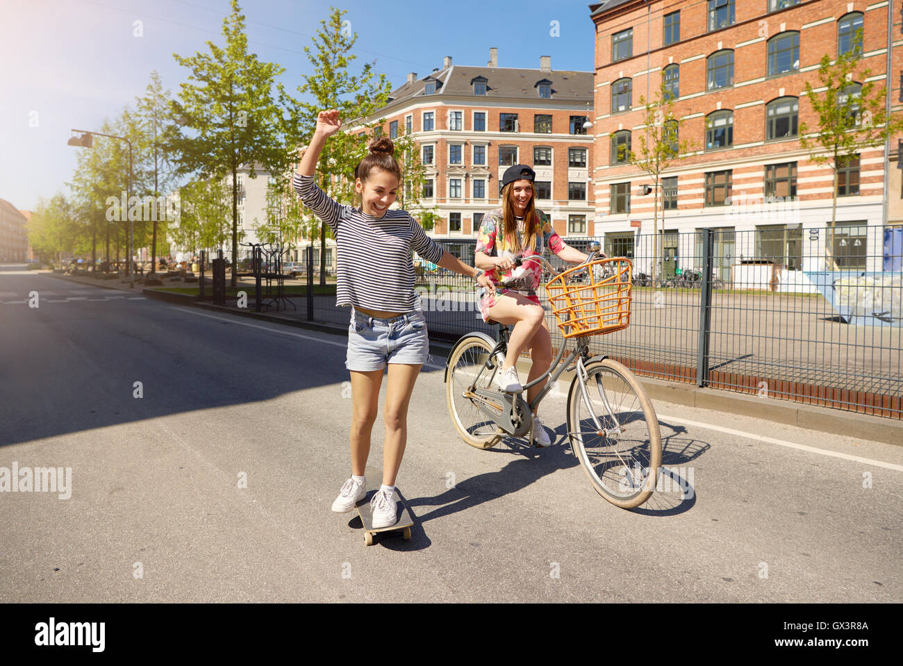Pair of cute female friends with excited expressions outside on paved ...