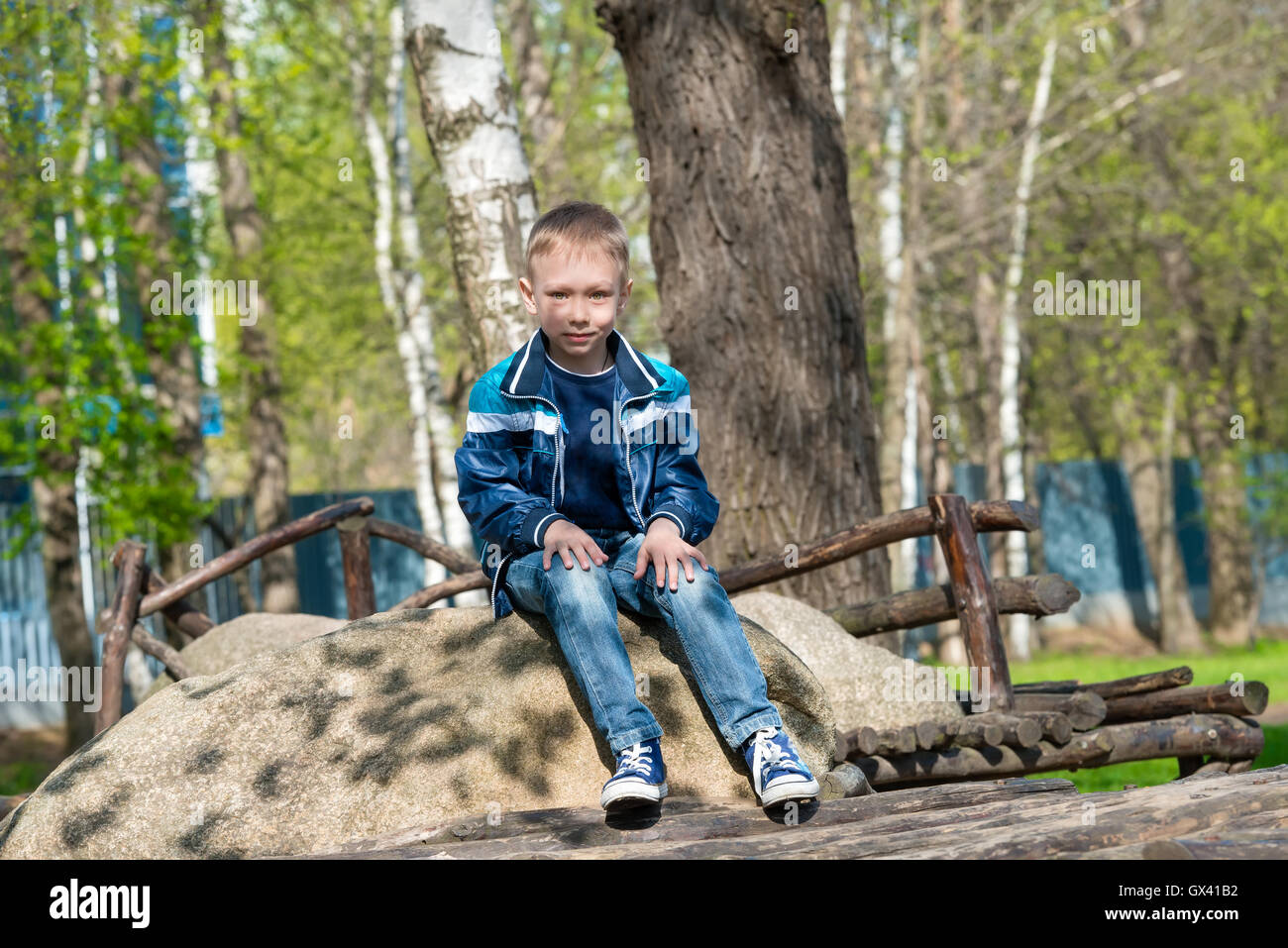 The boy takes a break from the games sitting on the stone Stock Photo ...