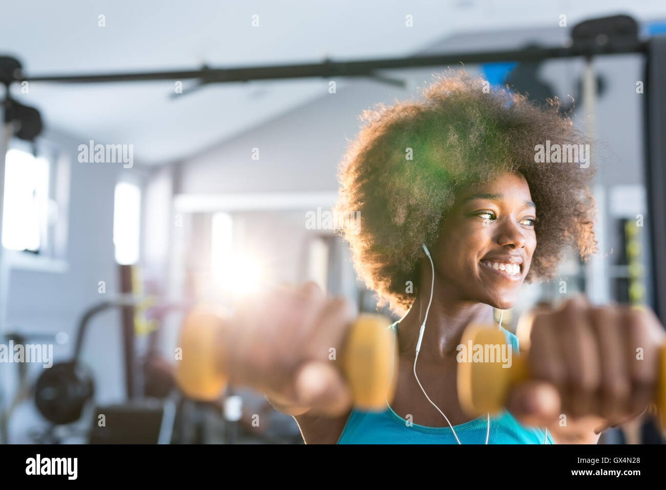 Happy healthy young African American woman working out in a gym with a ...