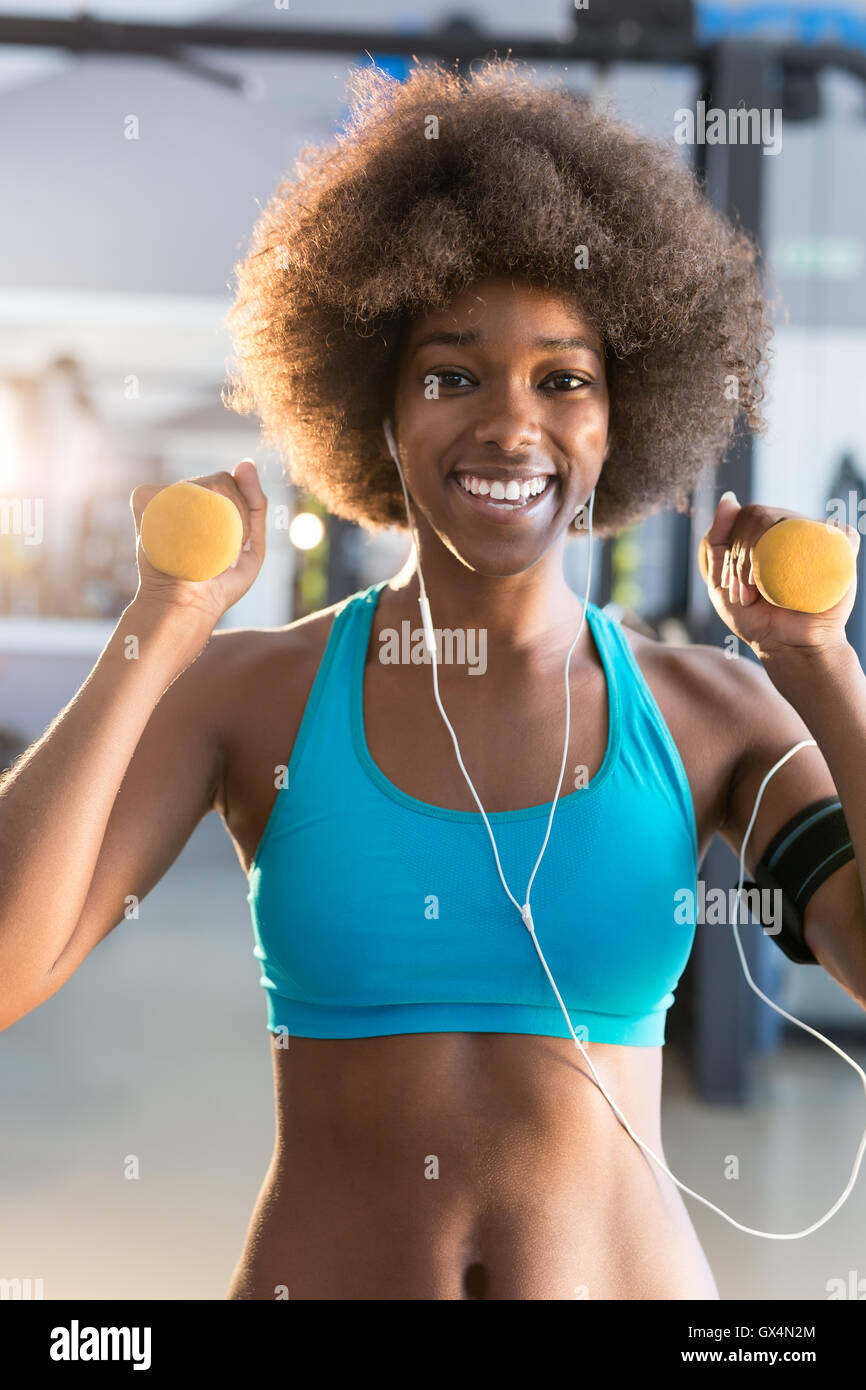 Happy healthy young African American woman working out in a gym with a ...