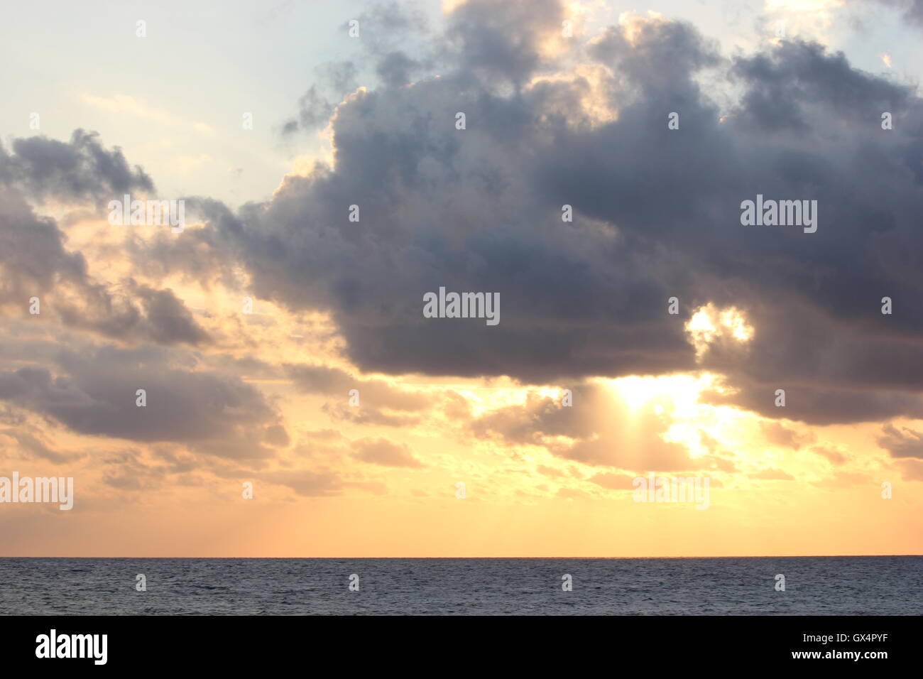 a beautifully moody sky with the sun behind the clouds, at sunset, with ...