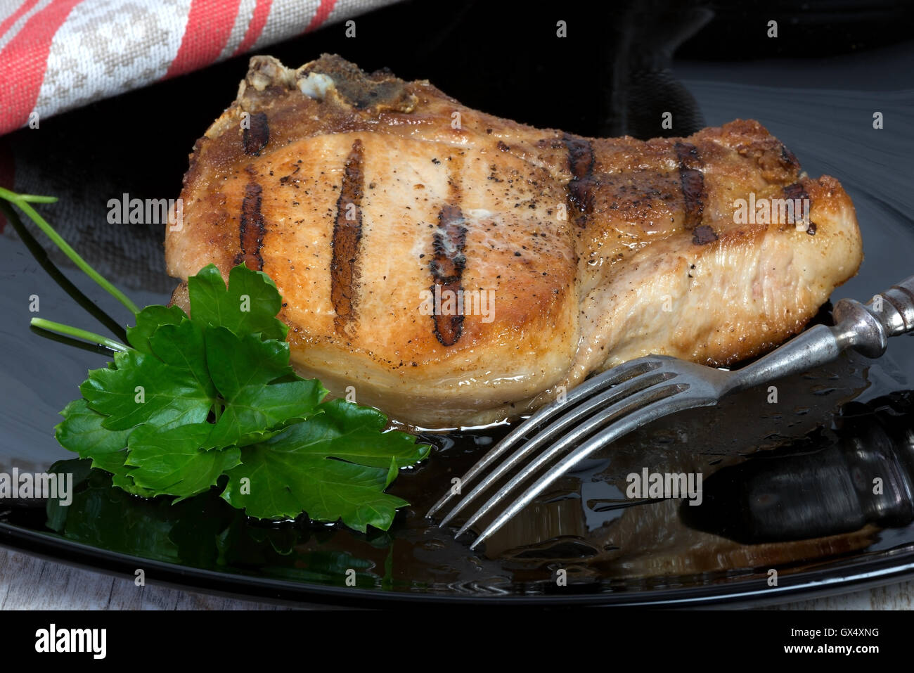 roast pork on a black plate and old fork Stock Photo - Alamy