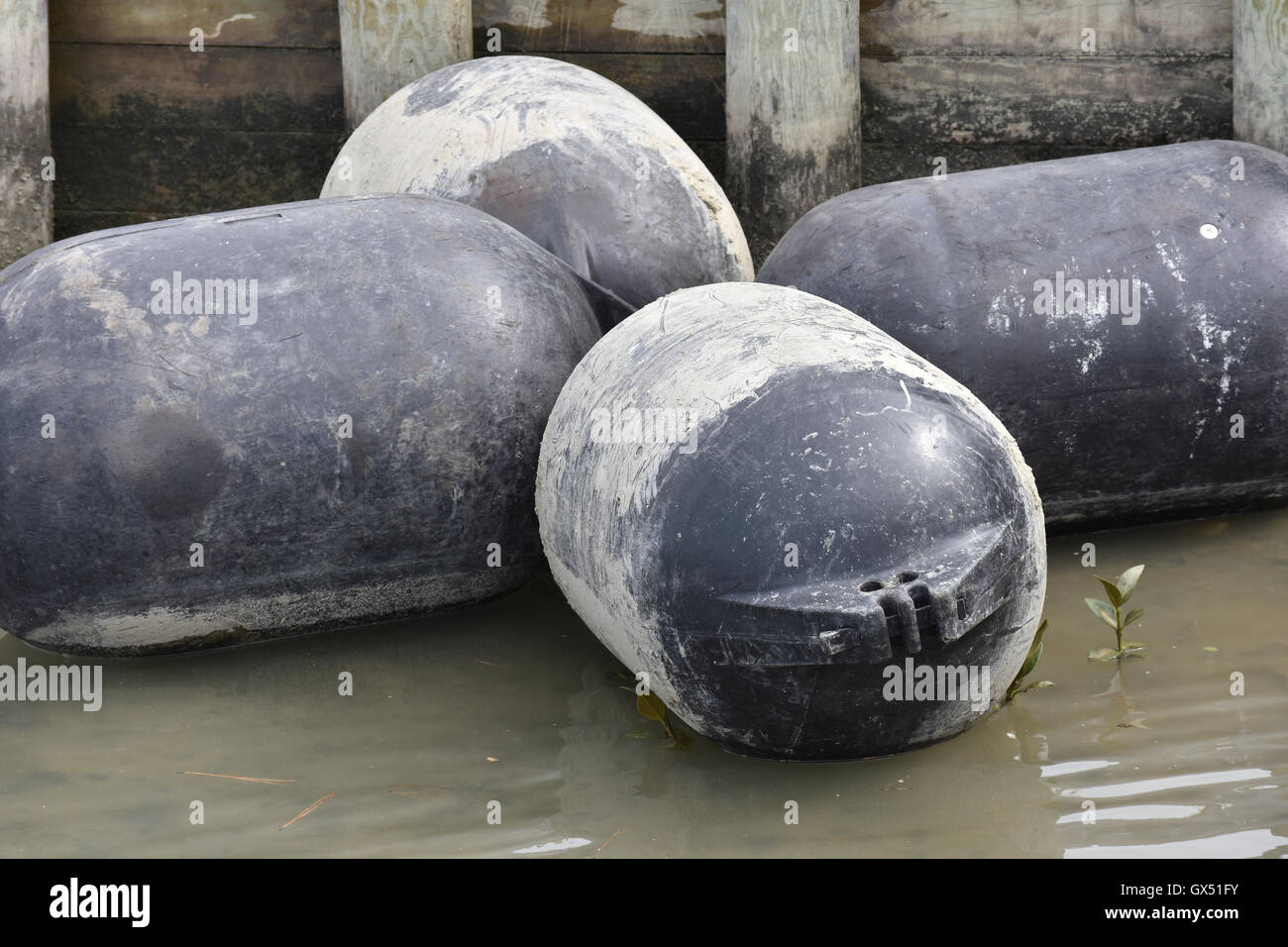 Black industrial fenders tied together at timber sea wall Stock Photo ...