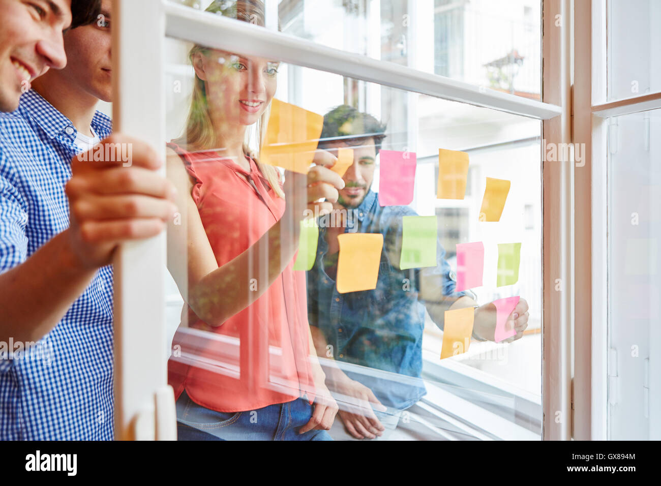 Team writing creative ideas on sticky notes for planning during ...
