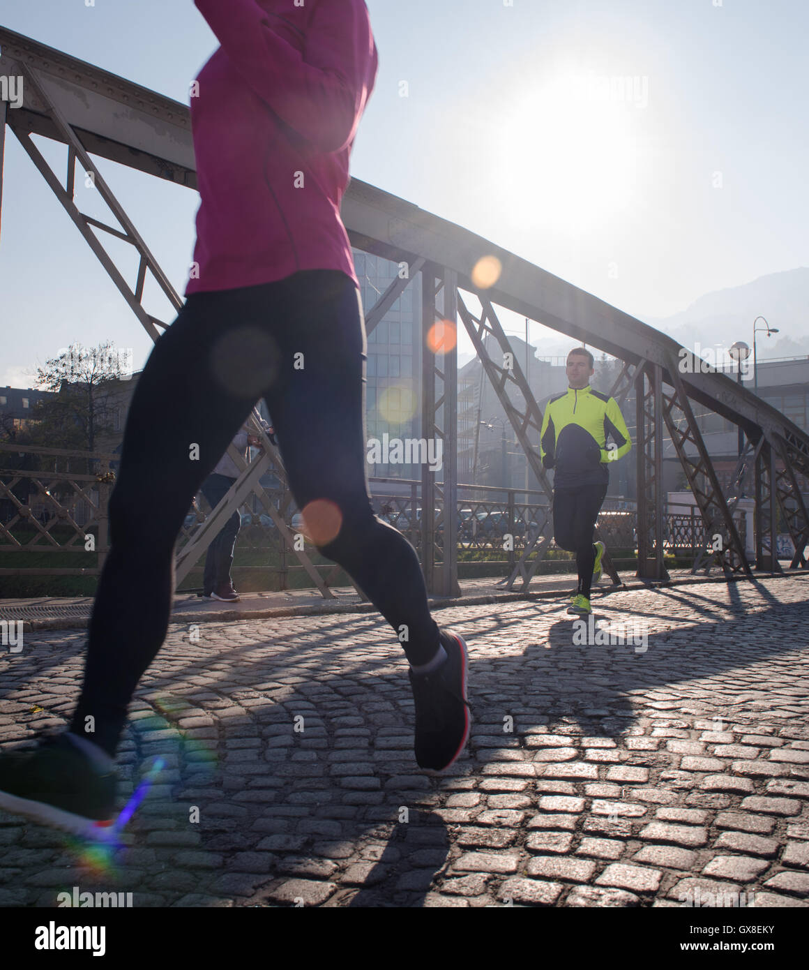 sporty woman running on sidewalk at early morning jogging with city ...