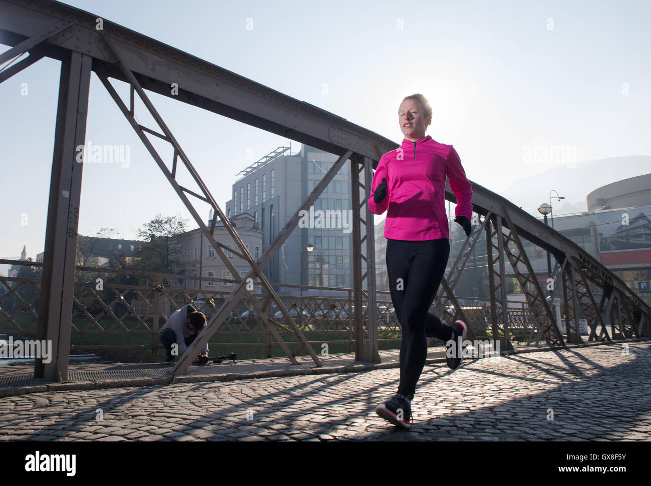 sporty woman running on sidewalk at early morning jogging with city ...