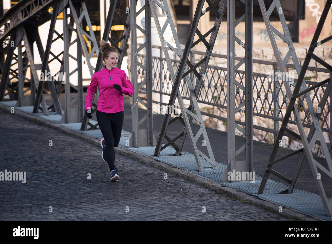 sporty woman running on sidewalk at early morning jogging with city ...
