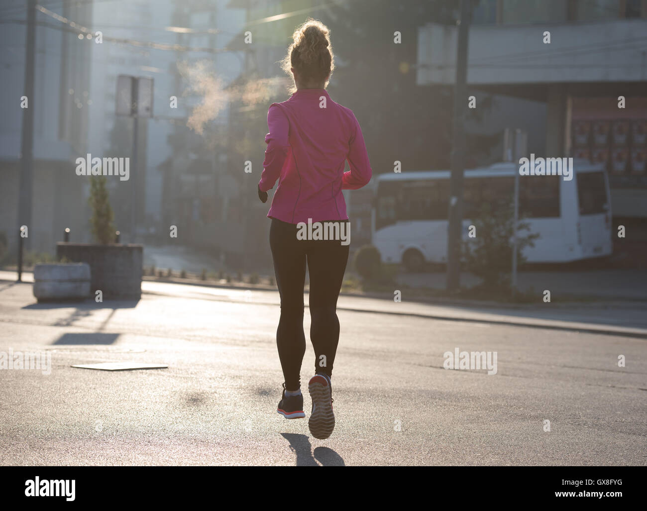 sporty woman running on sidewalk at early morning jogging with city ...