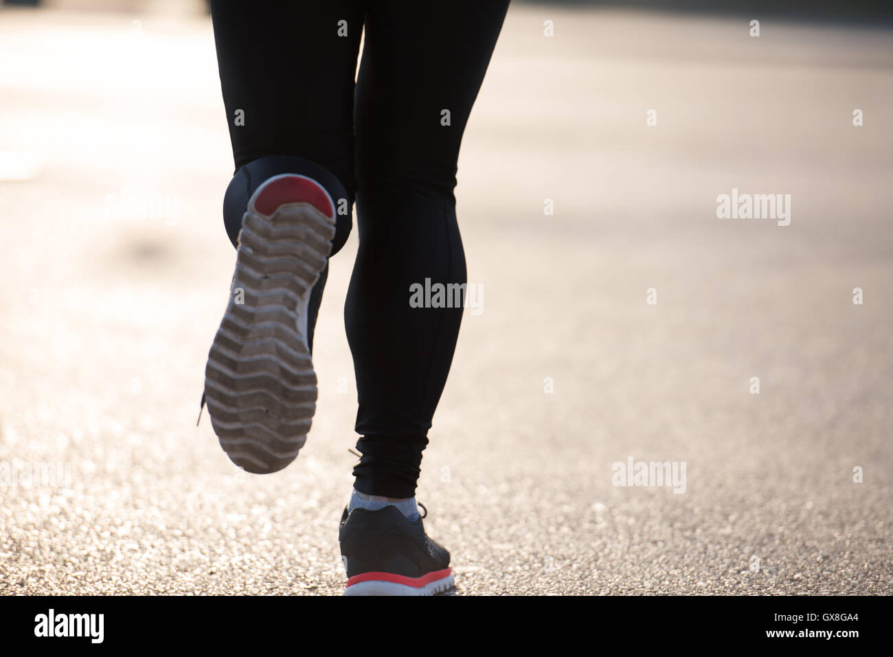 sporty woman running on sidewalk at early morning jogging with city ...
