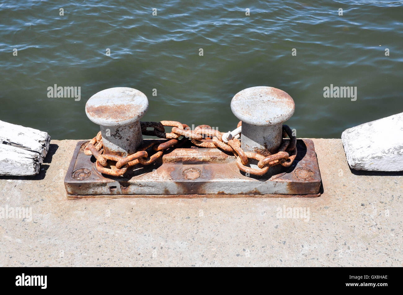 Jetty edge with rusted boat mooring and chain link in figure eight with ...
