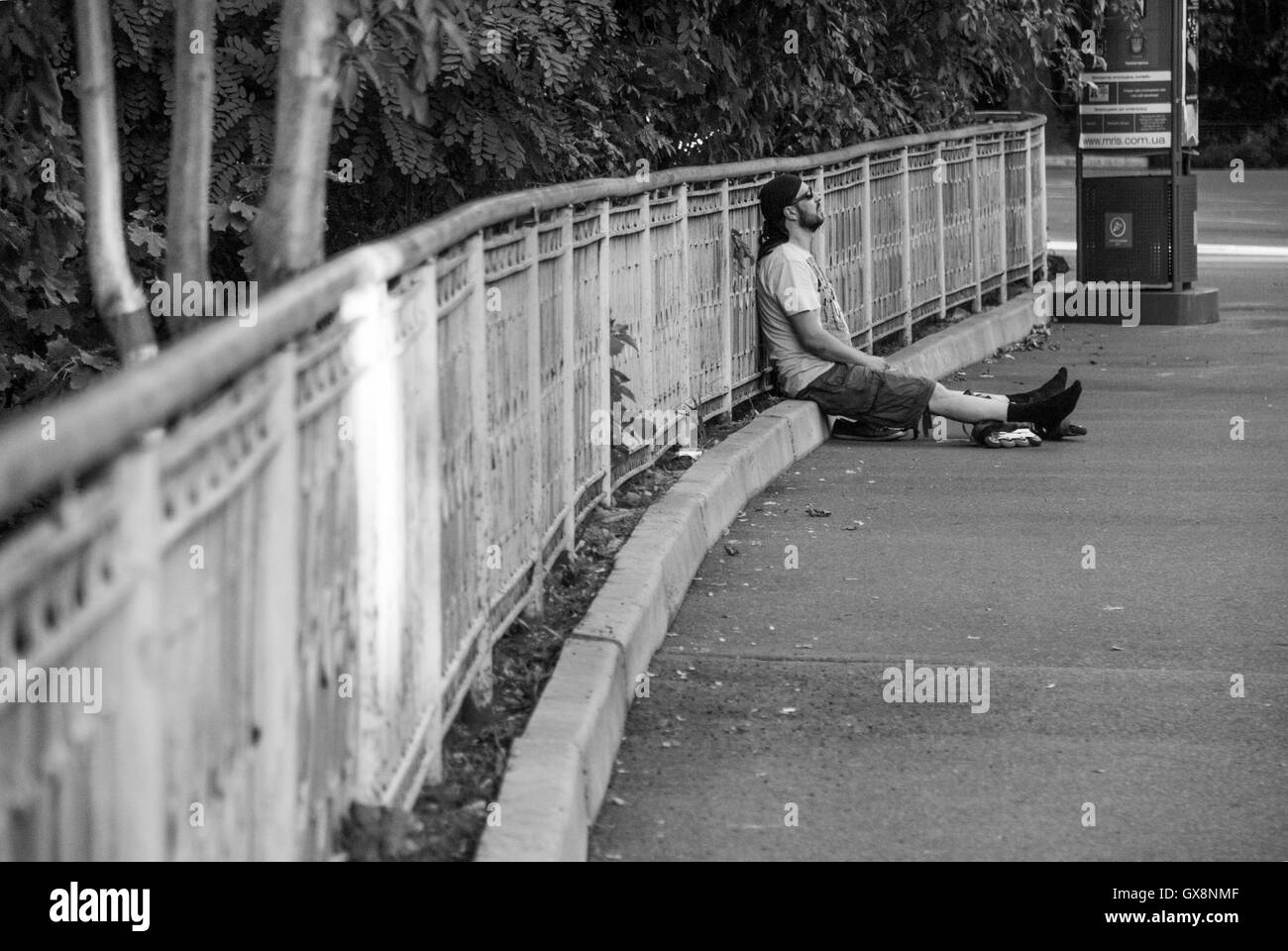A man with glasses and a bandana rest sitting near the parapet ...