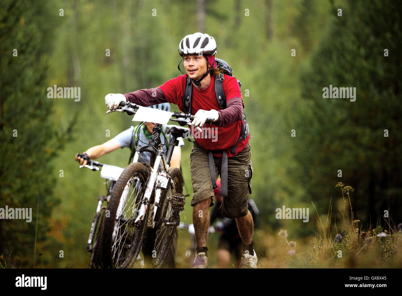 group of athlete mountainbikers climb a step uphill in forest during ...