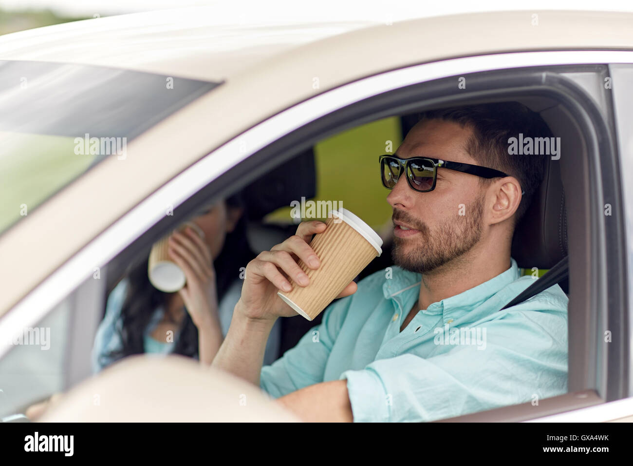 happy man and woman driving in car with coffee Stock Photo - Alamy