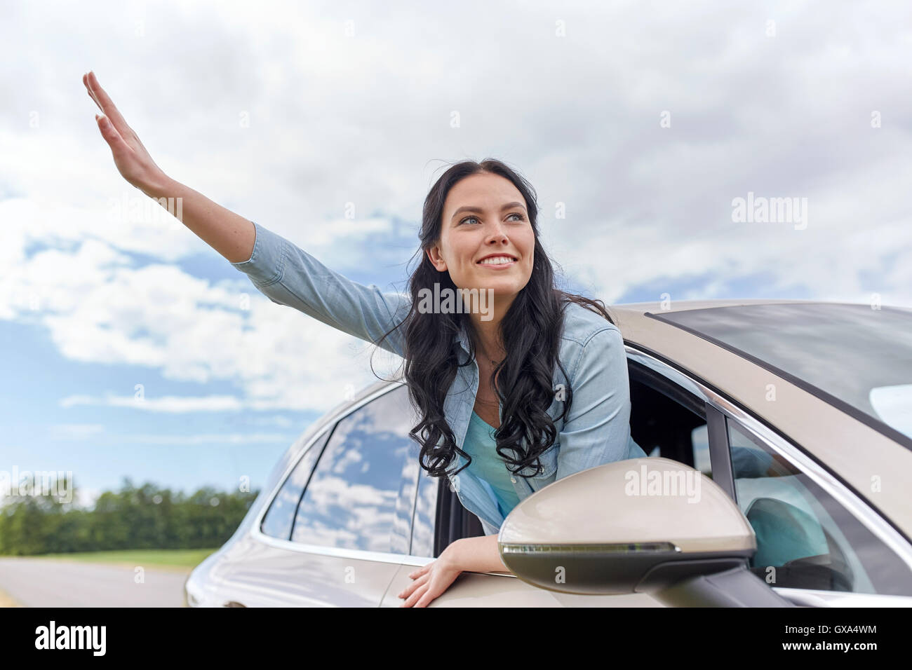 happy young woman driving in car and waving hand Stock Photo - Alamy