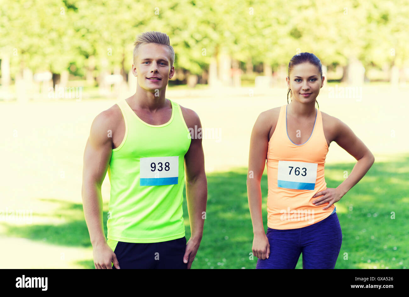 happy friends or couple with racing badge numbers Stock Photo - Alamy