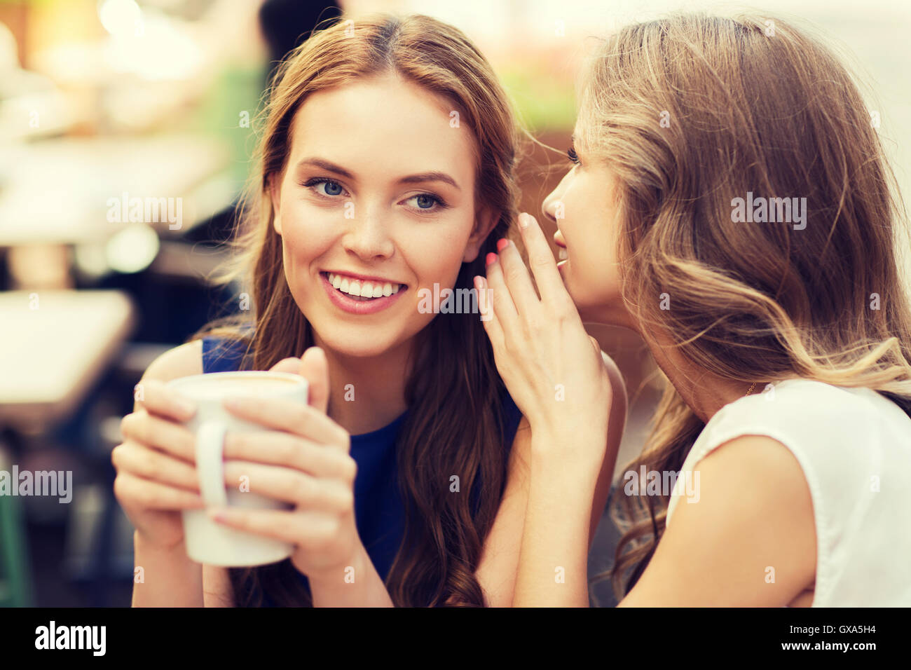 young women drinking coffee and talking at cafe Stock Photo - Alamy