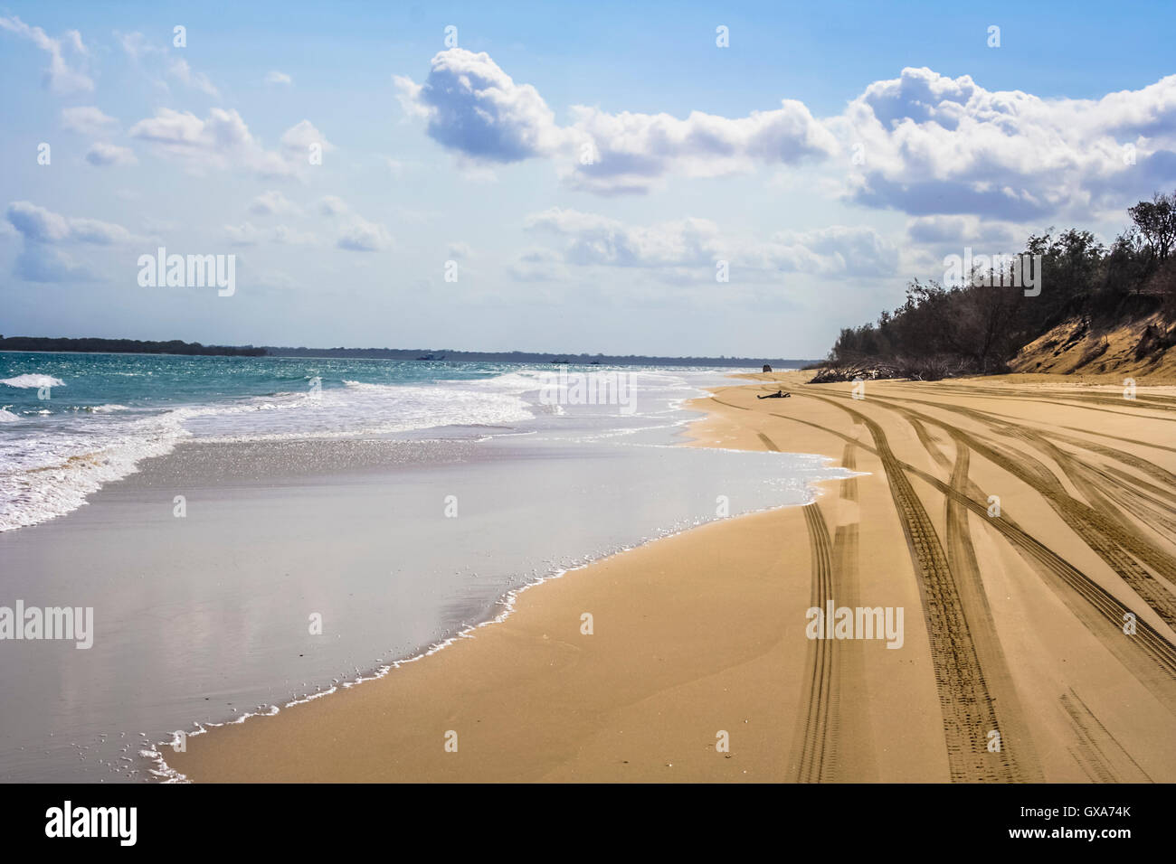 Four wheel drive tracks on Fraser Island sandy beach with boats and ...