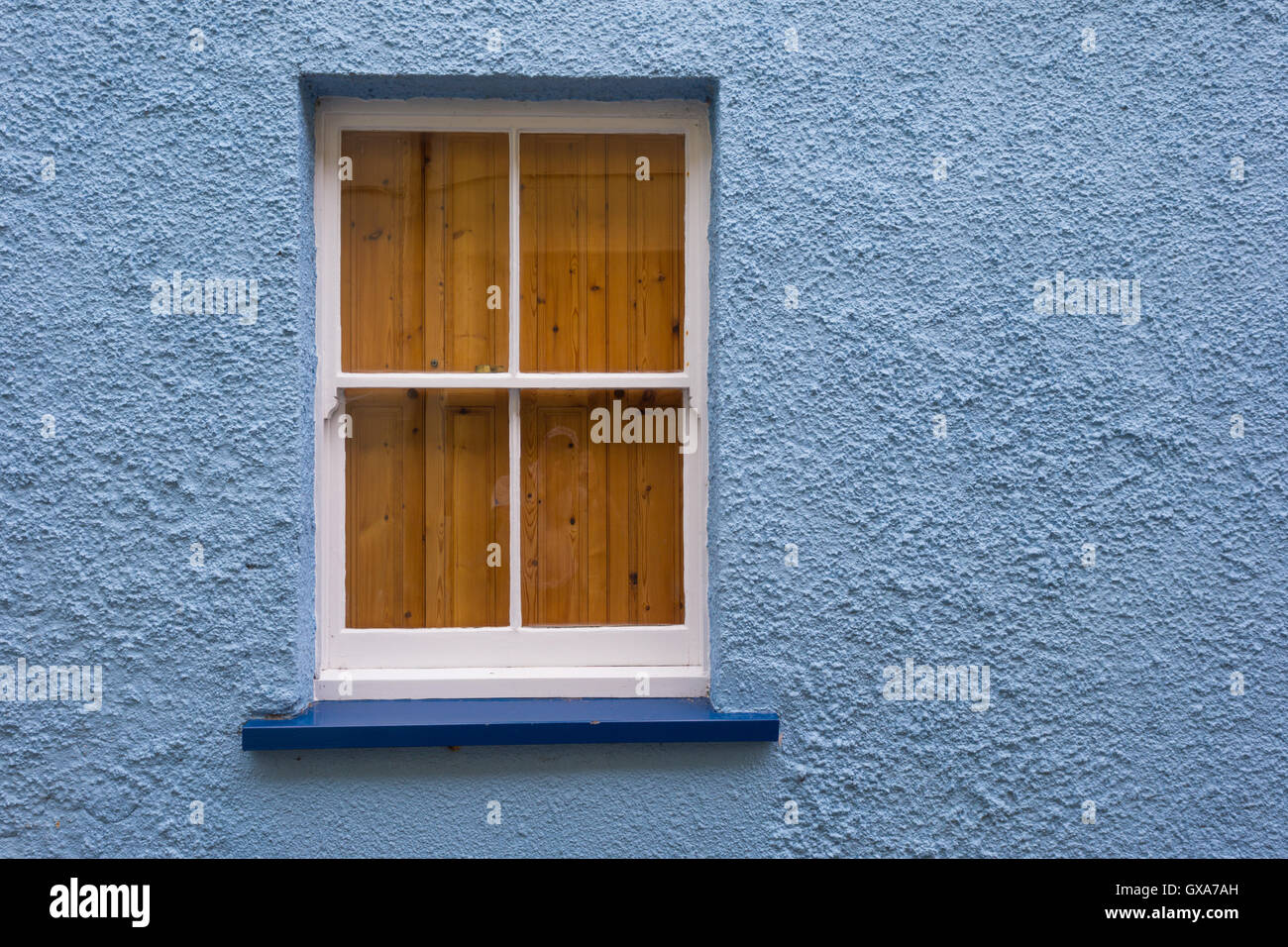 Window on a blue painted outer wall of a house in Lyme Regis, Dorset UK ...