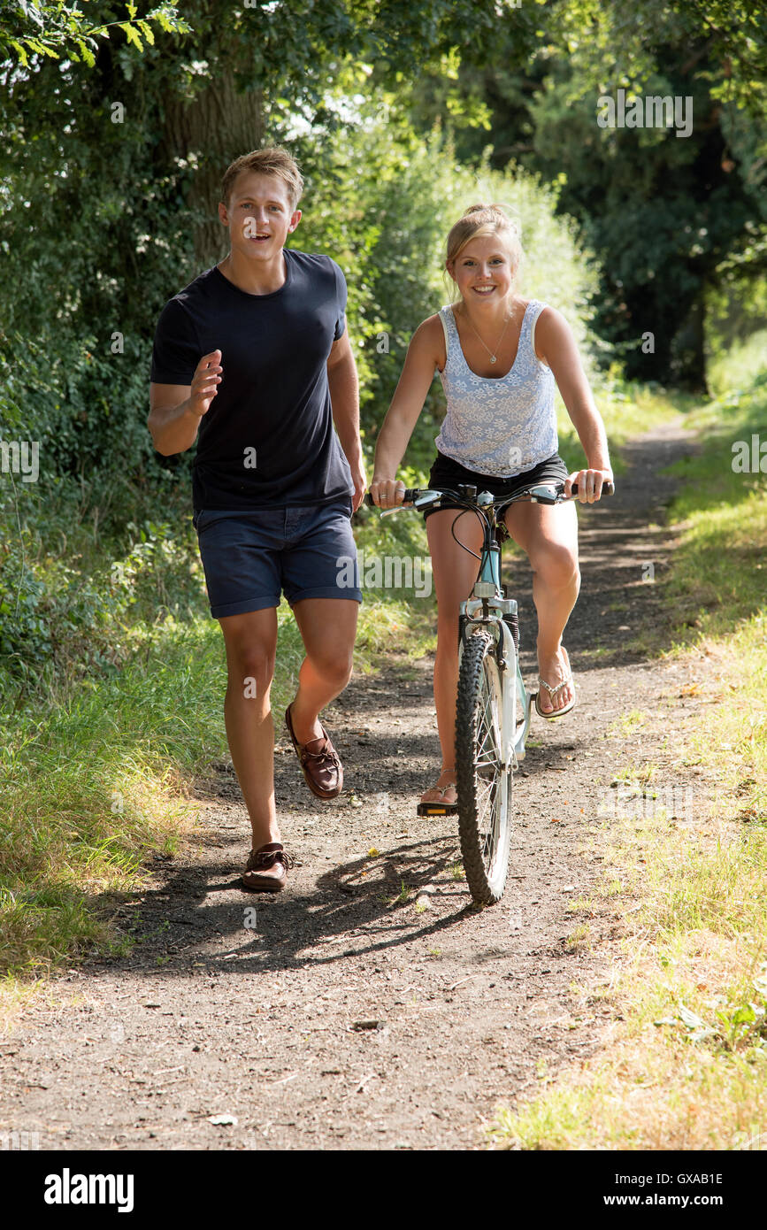 Teenage girl riding a bicycle - Teenager boy running with his female ...
