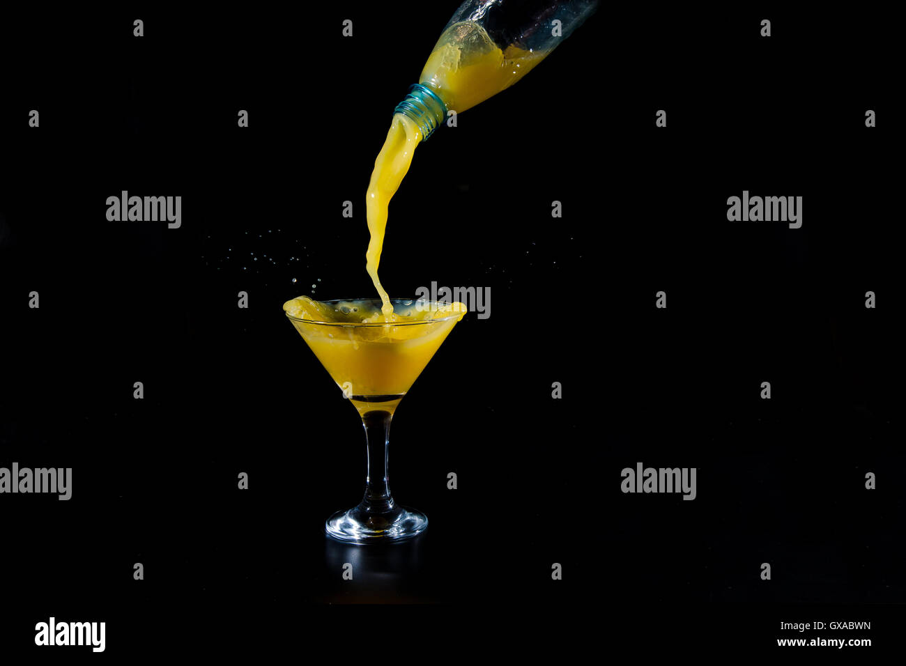 orange juice is being poured into a glass beaker from a bottle on black ...