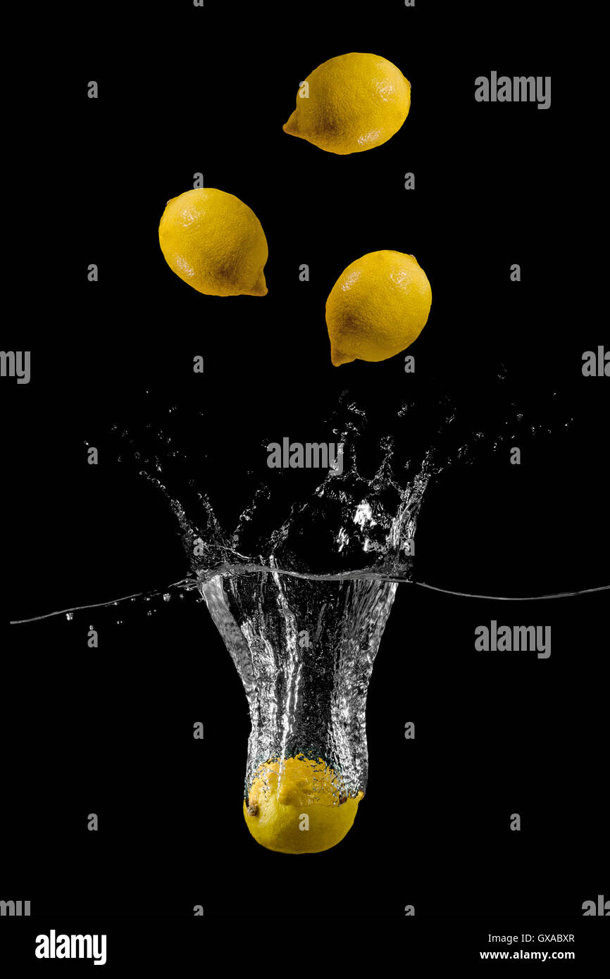 Lemons are falling into the water holding up a lot of splashes on a ...