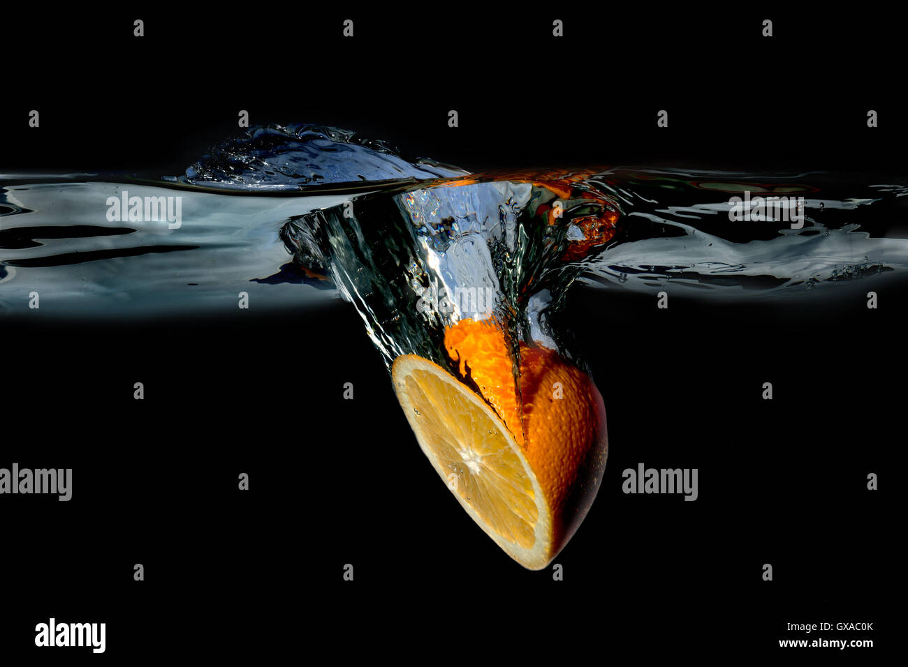 Orange in water raised a big wave on a dark background Stock Photo - Alamy