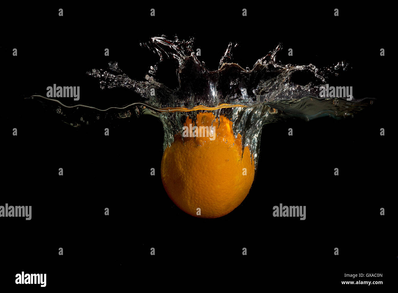 Orange in water raised a big wave on a dark background Stock Photo - Alamy