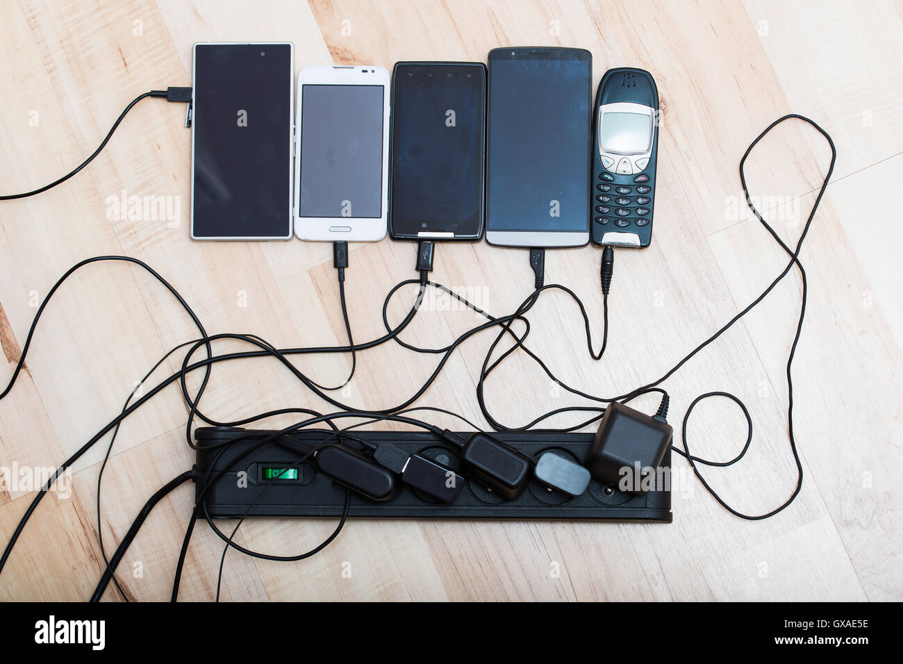 four smartphones and one classic phone connected to chargers Stock ...