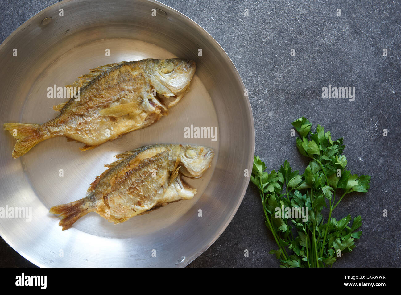 Fried fish in an old pan on the table, top view Stock Photo - Alamy