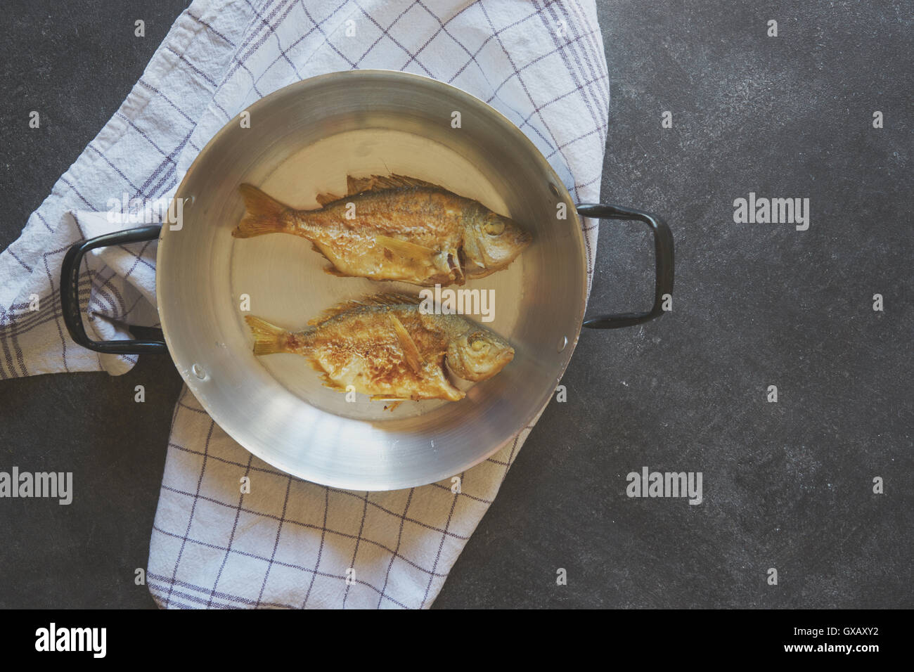Fried fish in an old pan on the table, top view Stock Photo - Alamy