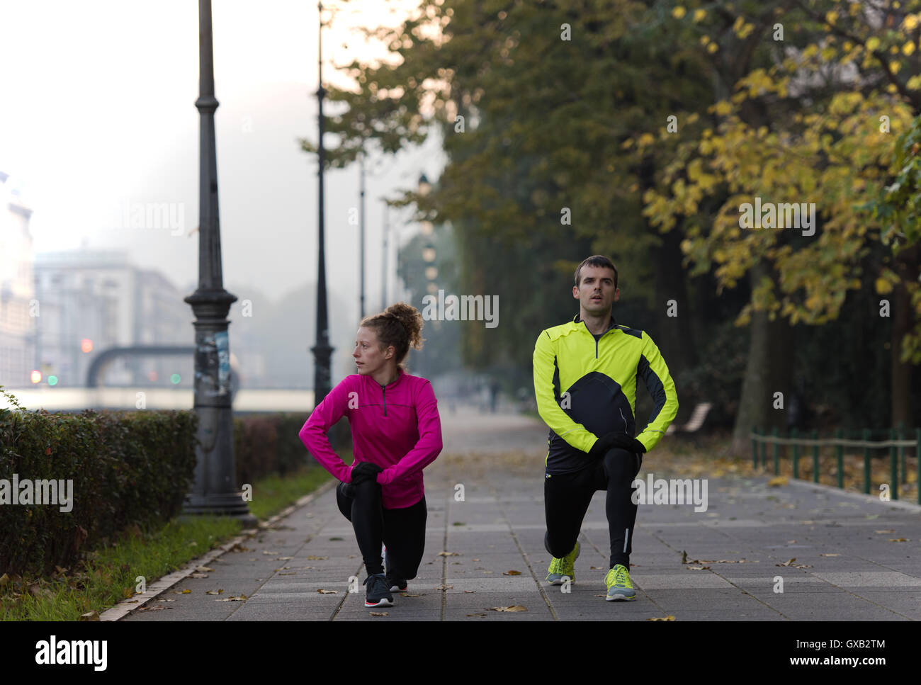 jogging couple warming up and stretching before morning running in the ...