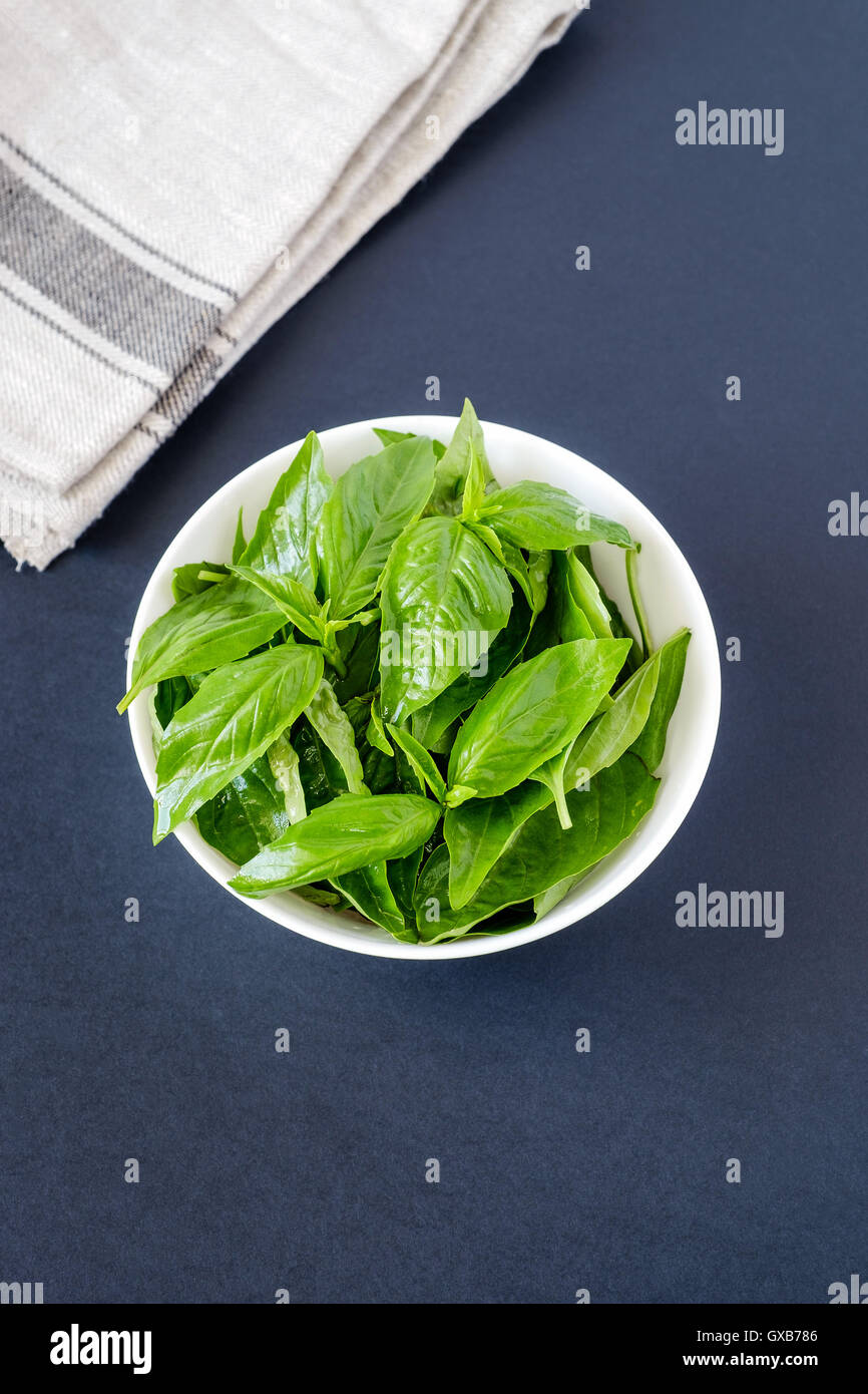 leaves of fresh spicy Basil in a white plate on a dark background Stock ...