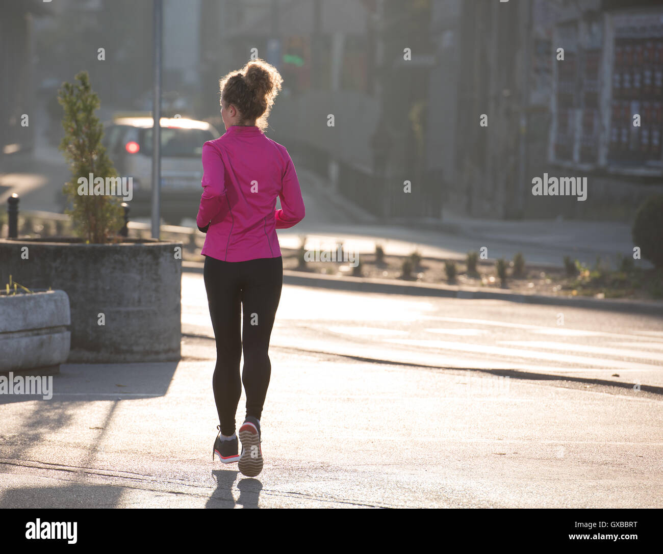 sporty woman running on sidewalk at early morning jogging with city ...