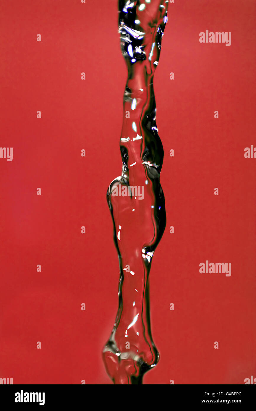 Water falling down, frozen in time with red background Stock Photo - Alamy