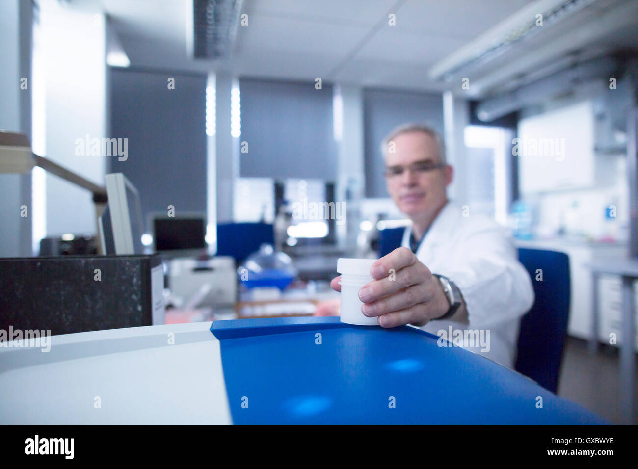 Male meteorologist placing sample bottle on bench in weather station ...