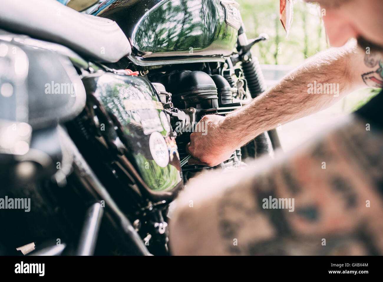Cropped shot of male motorcyclist crouching to repair motorcycle Stock ...