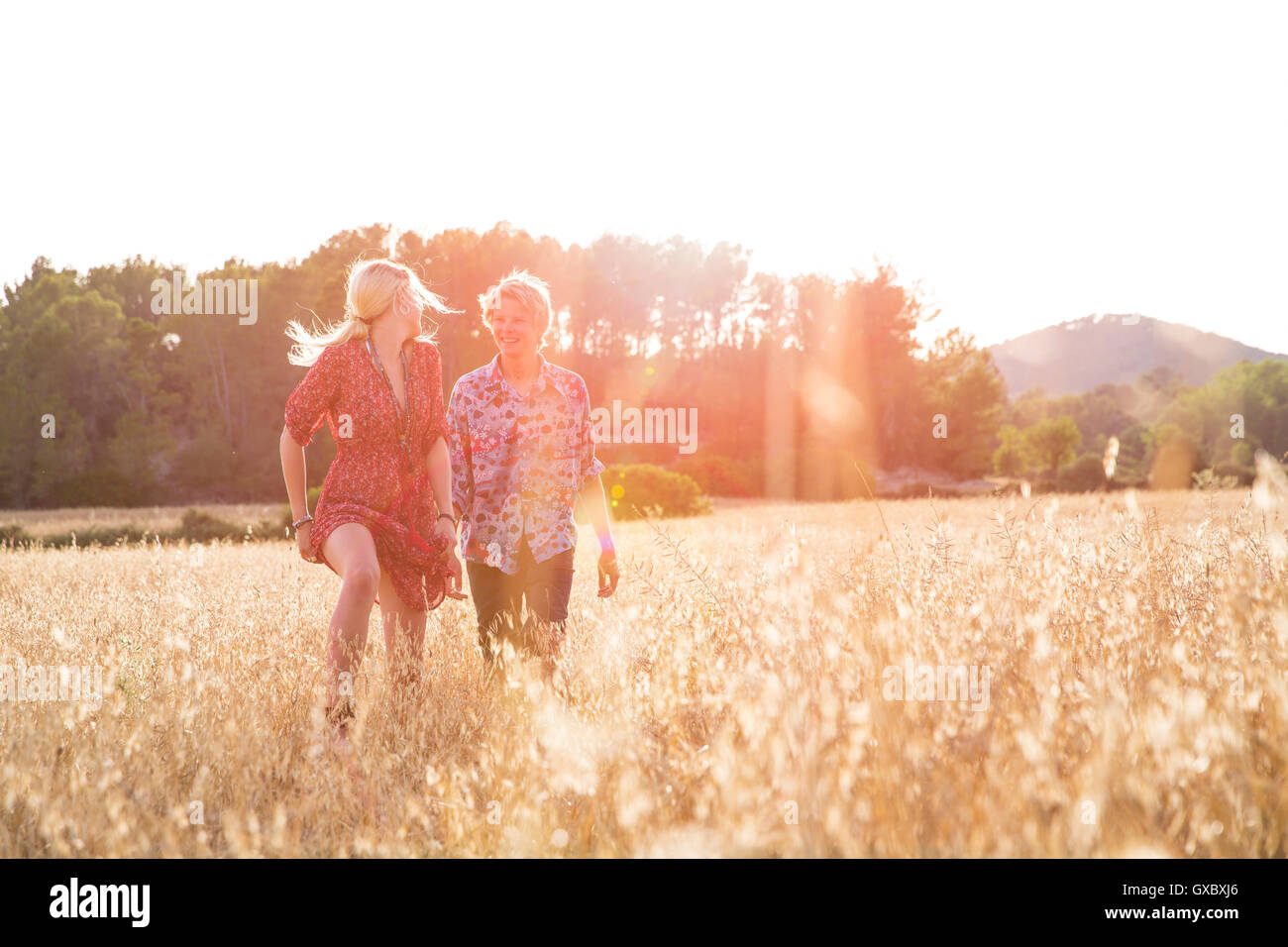 Young woman looking back at boyfriend running in wheat field, Majorca ...