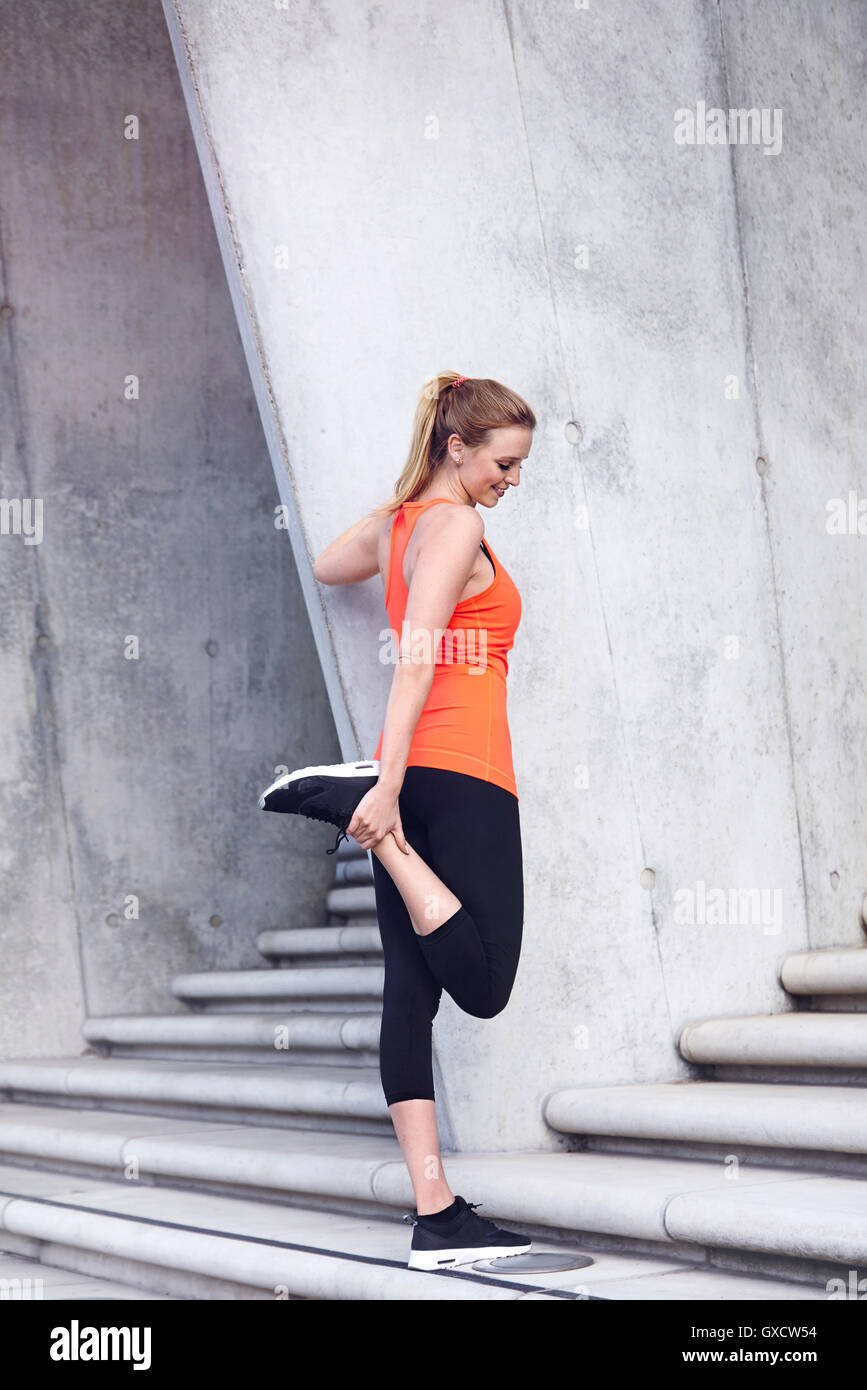 Woman on steps holding ankle stretching leg Stock Photo - Alamy