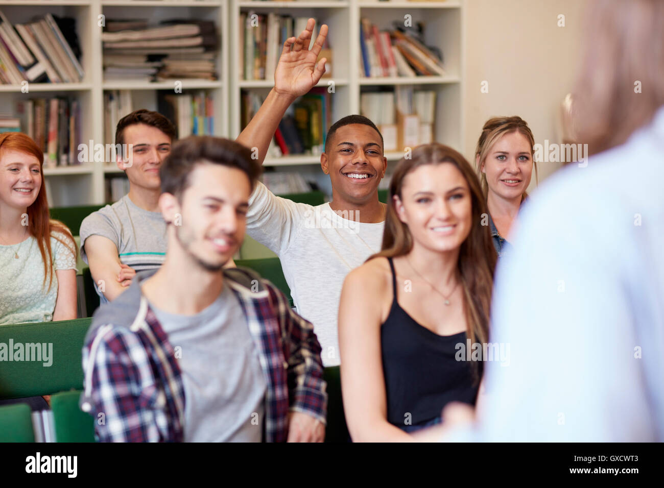 Male student questioning lecturer in higher education college classroom ...