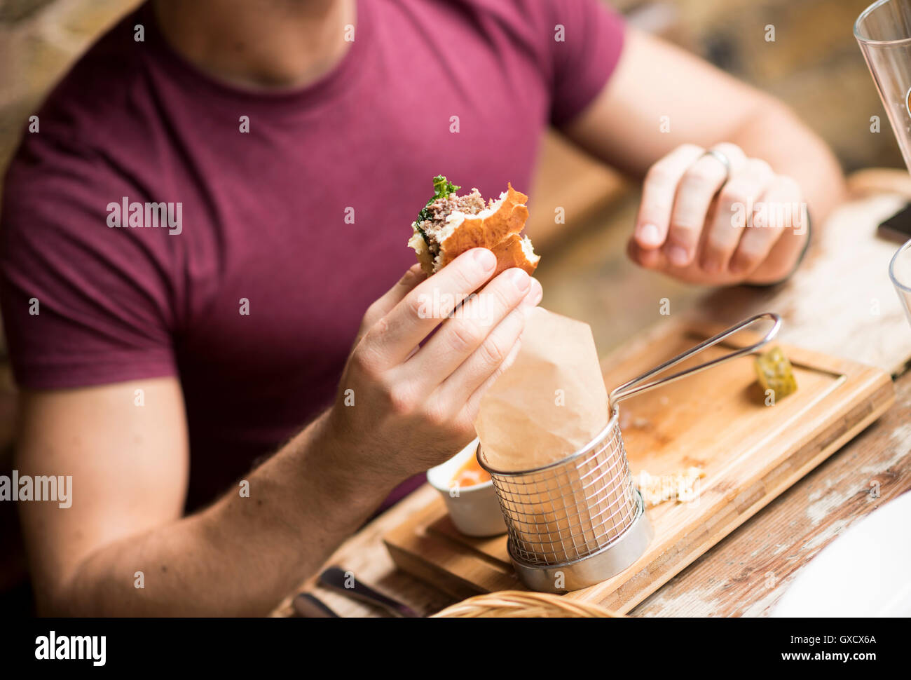 Cropped shot of young man eating burger in restaurant Stock Photo - Alamy